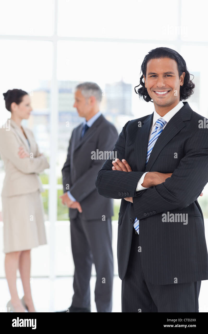 Young smiling executive standing upright in front of two business ...