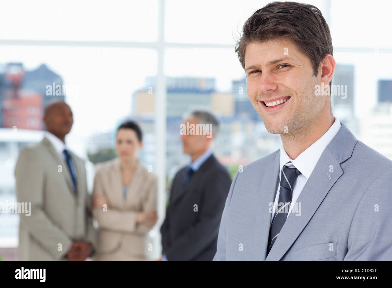 Smiling businessman standing upright with his team between him Stock ...