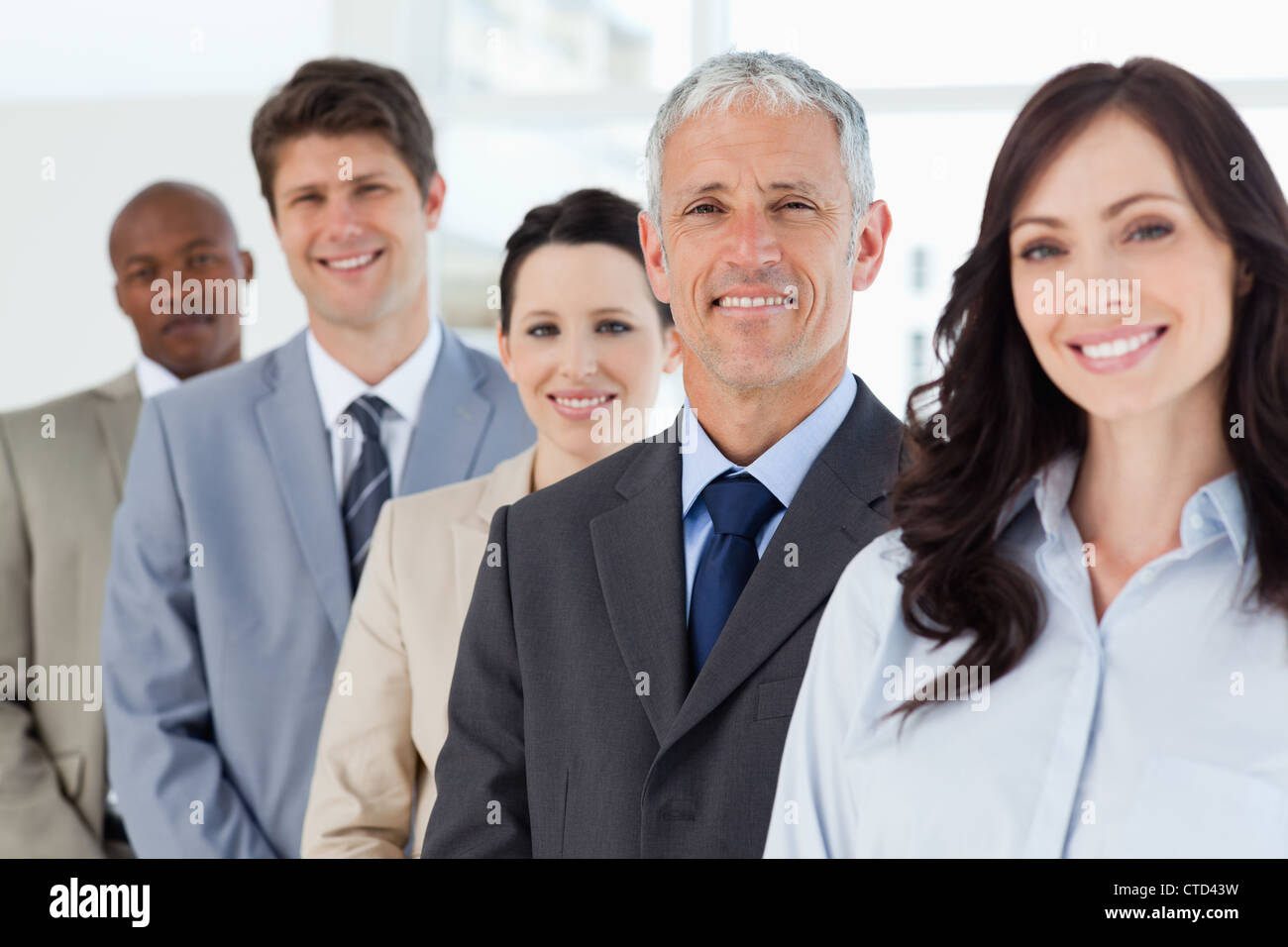 Four smiling employees standing upright around their director Stock ...
