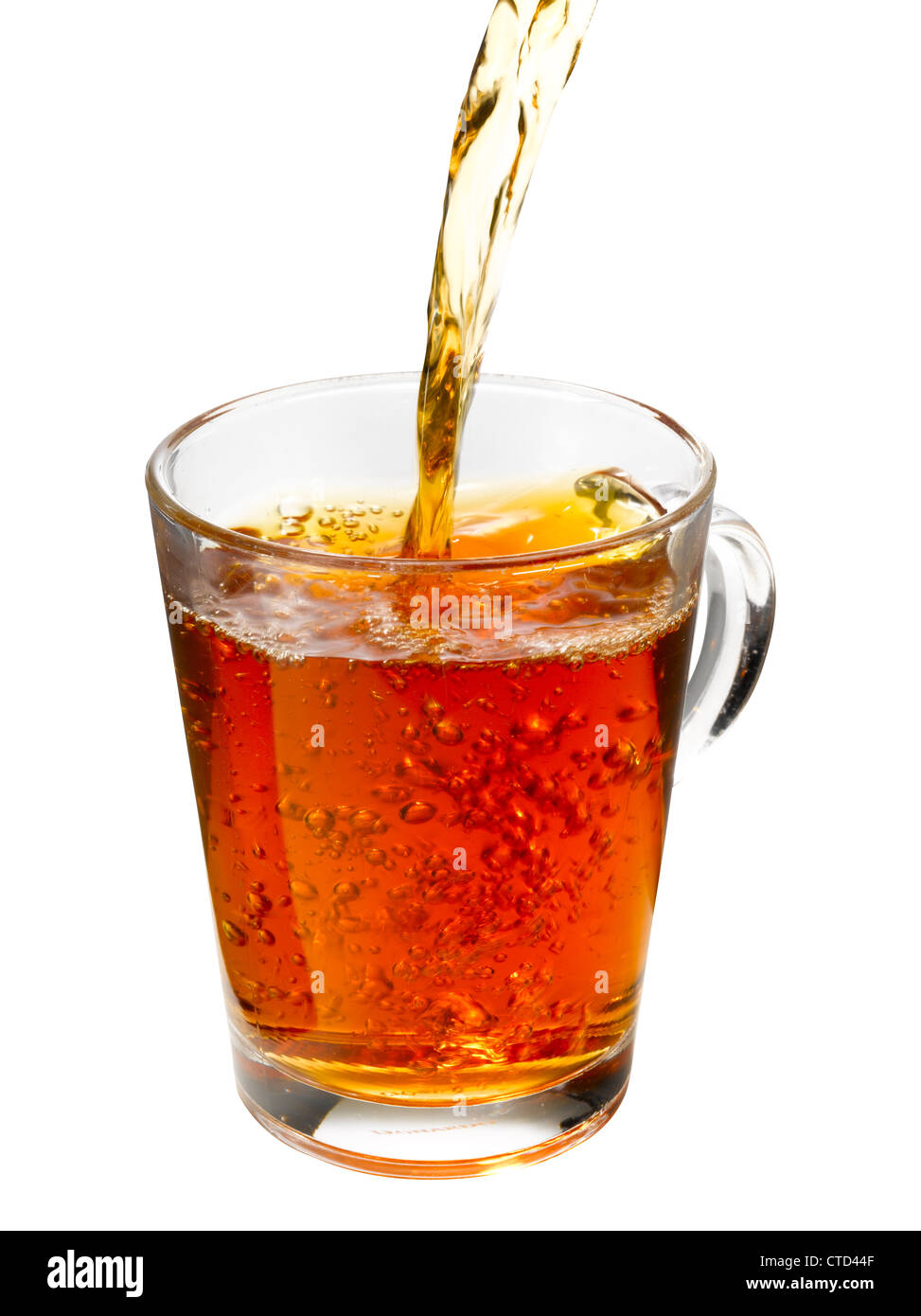 A stream of tea falling in a cup. The cup is filled with tea and ...