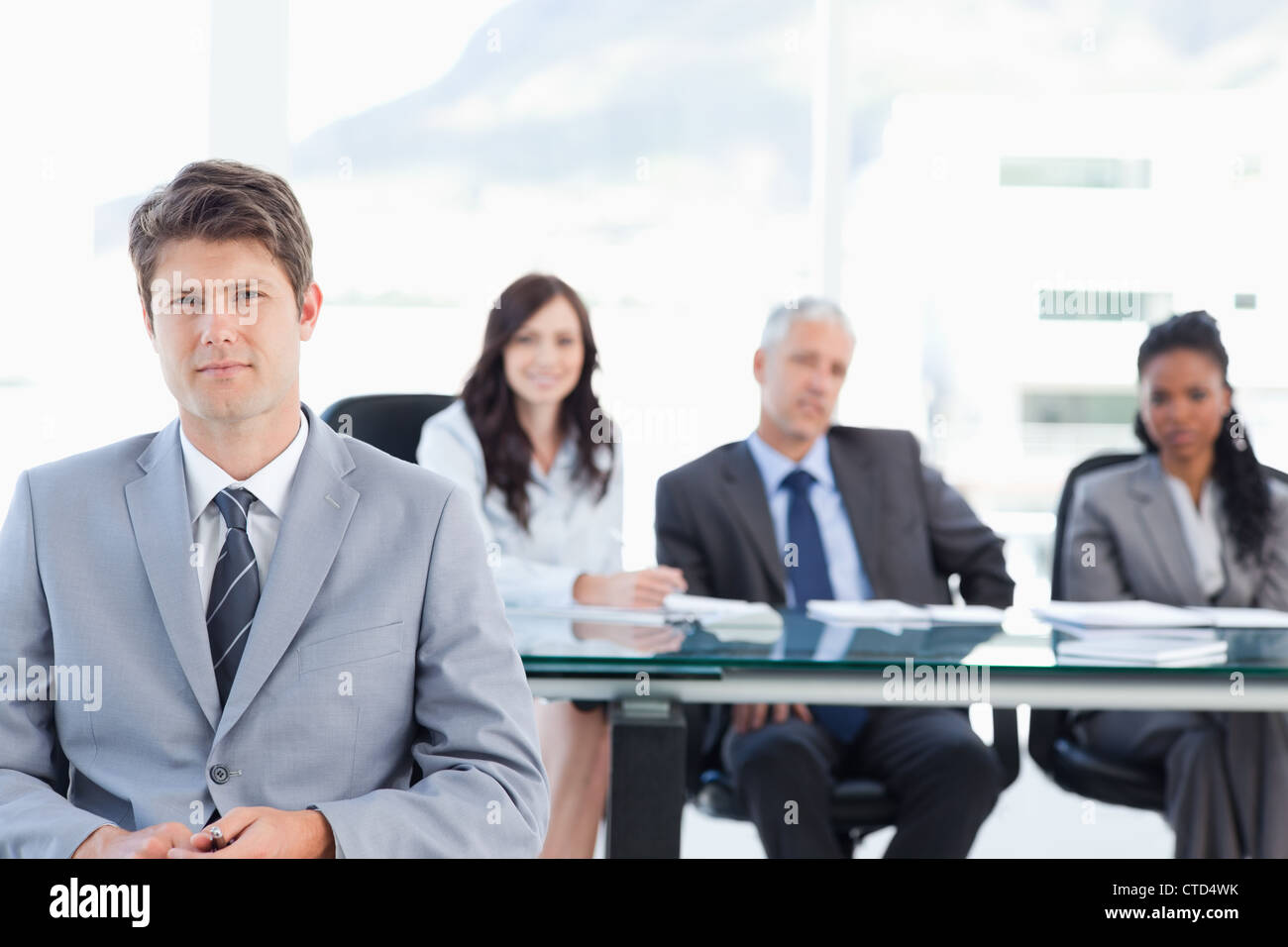 Earnest executive sitting in front of his team in a bright room Stock ...