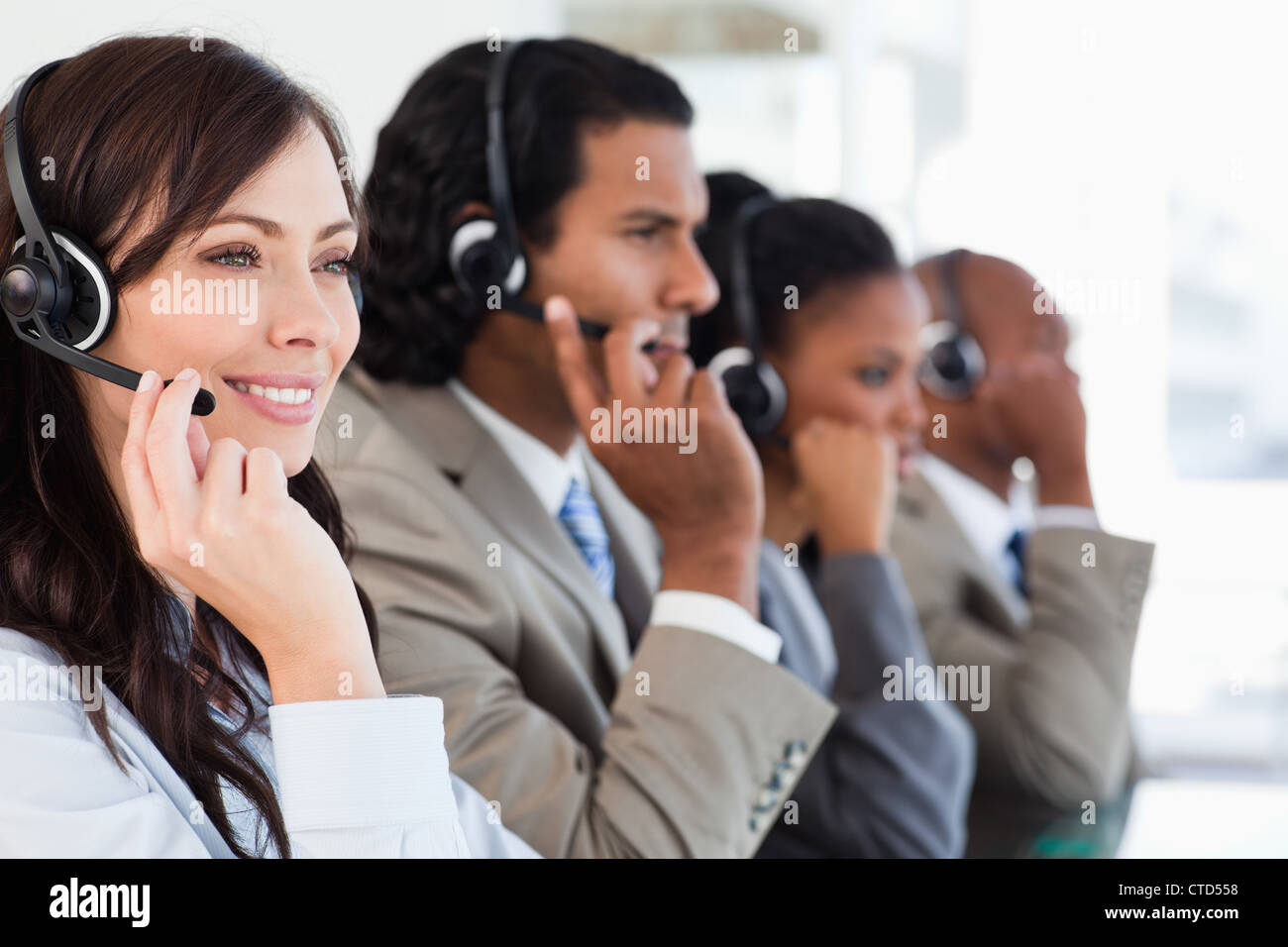 Smiling call centre employee working while accompanied by her team ...