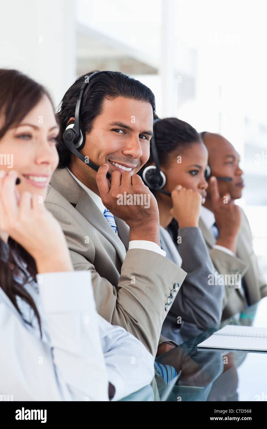 Young smiling call centre worker working among his business team Stock ...
