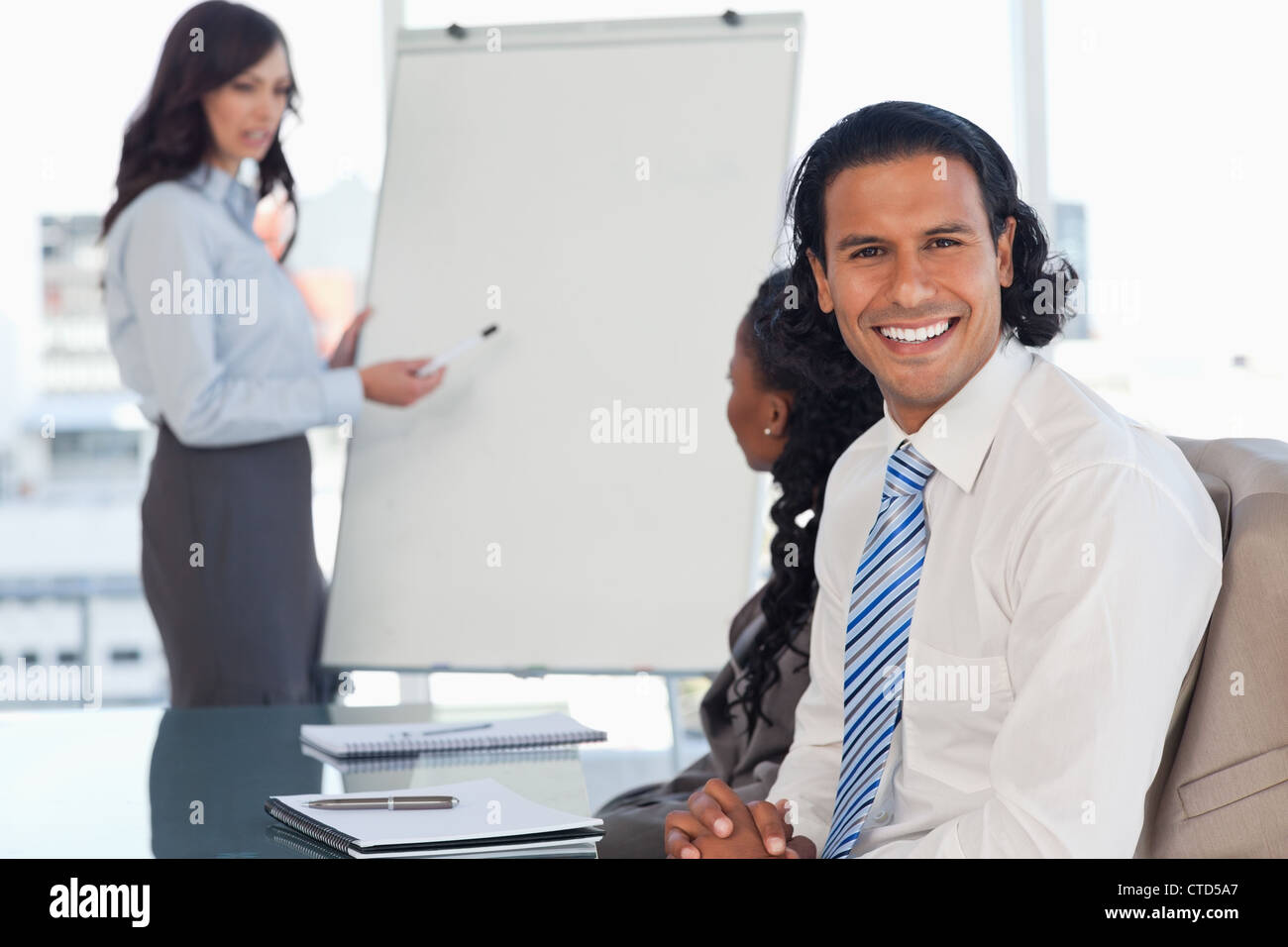 Young employee smiling during a presentation while his team is working ...