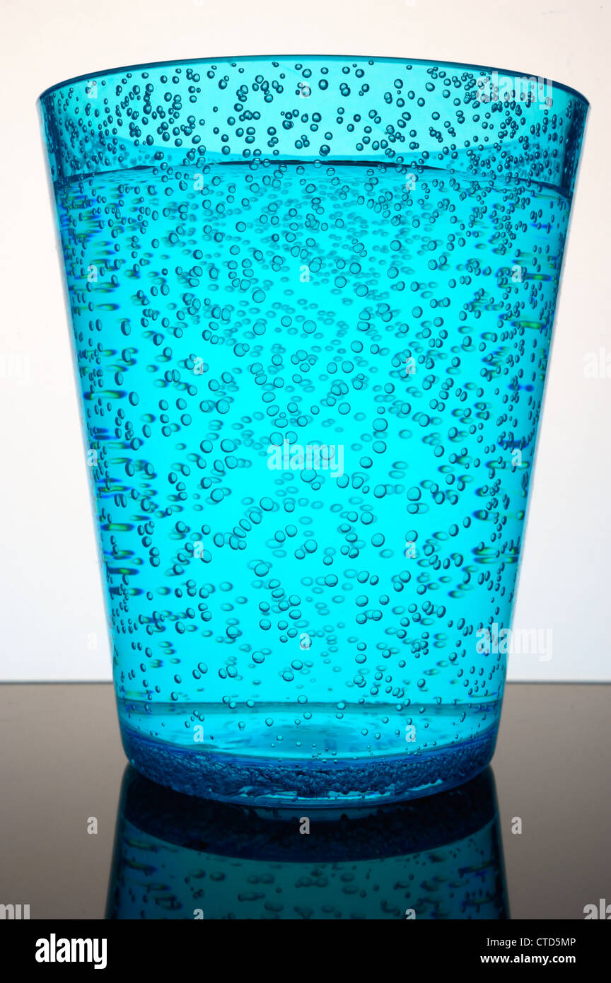 Water in the glass with bubbles and reflection on the dark background ...