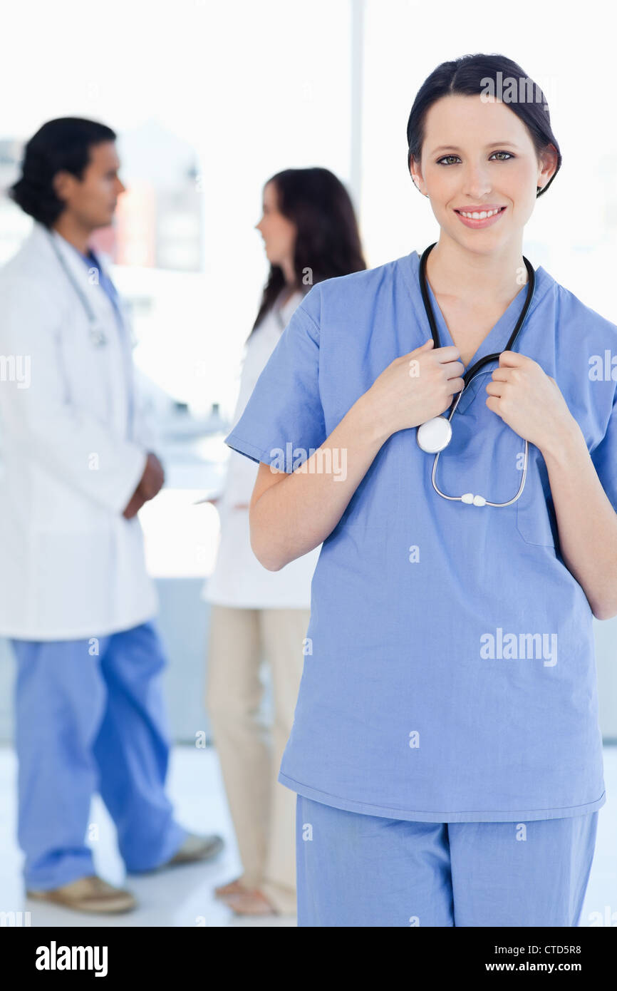 Young smiling medical intern wearing her uniform and standing in front ...