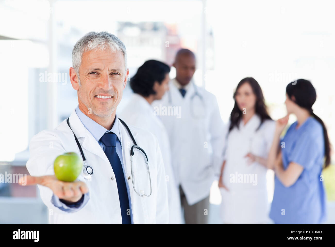 Mature doctor holding an apple in his right hand Stock Photo - Alamy