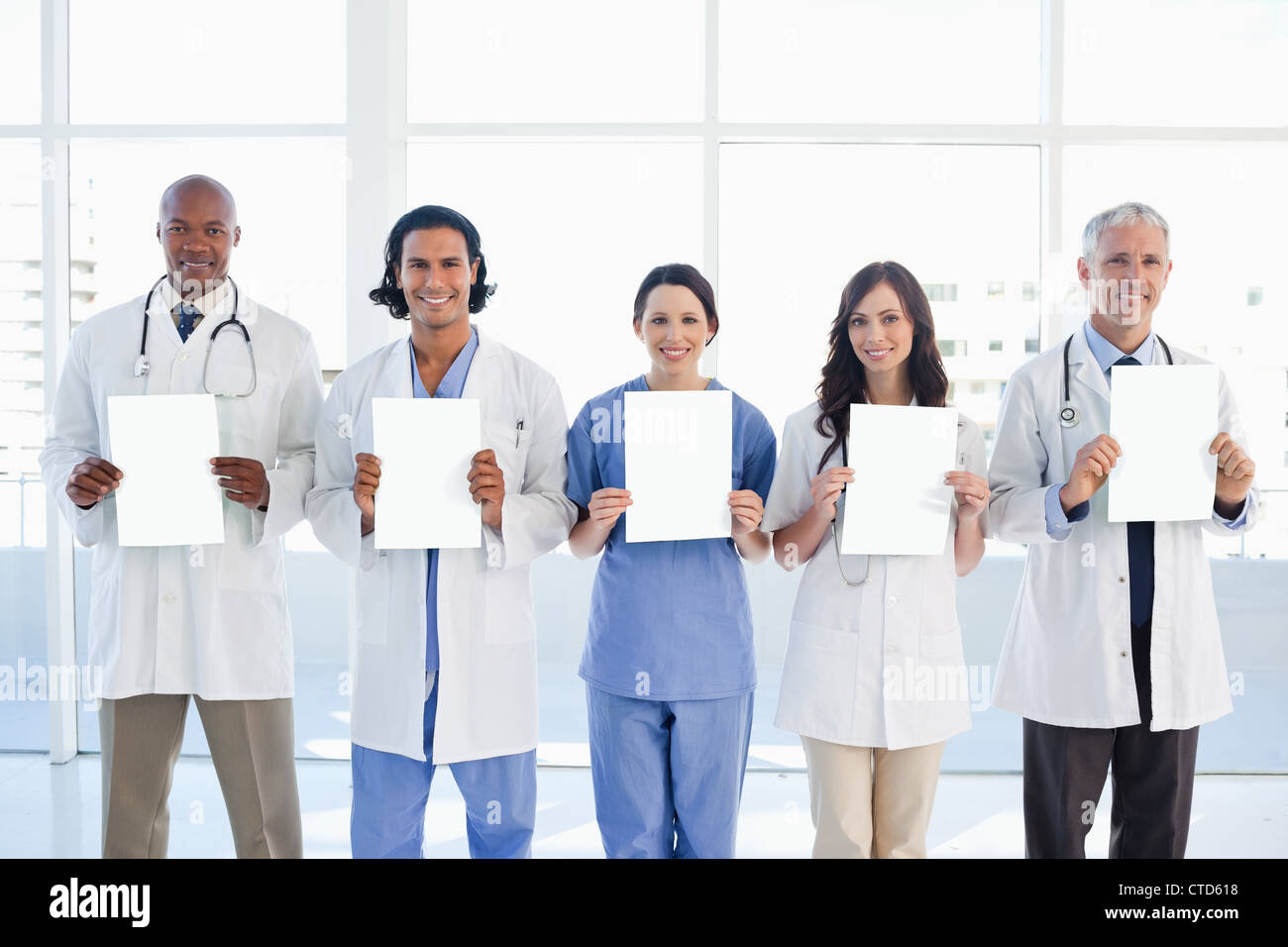 Medical team standing upright in front of the window while showing ...
