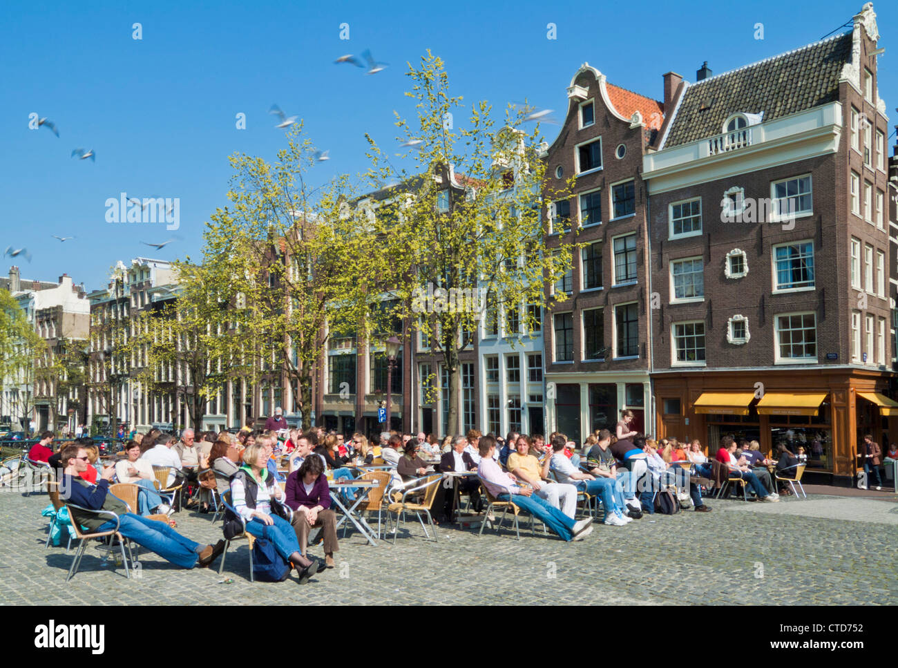 Crowds enjoying a drink in a cafe by the Singel canal central Amsterdam ...