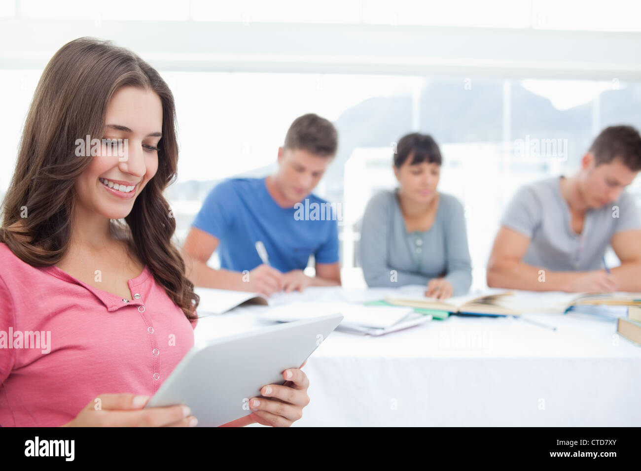 A smiling woman in front of her friends on her tablet Stock Photo - Alamy