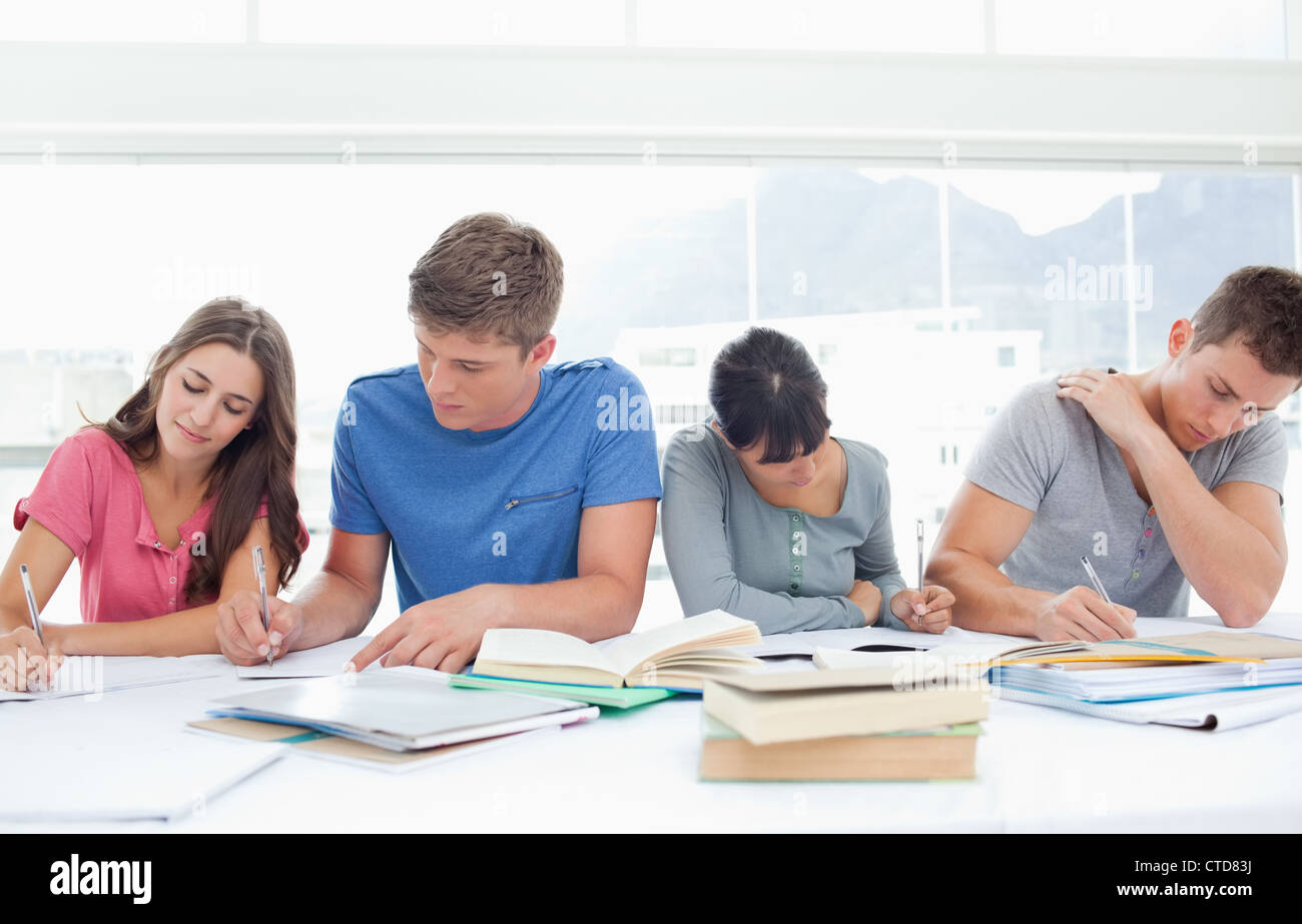 Four students sit beside each other and study Stock Photo - Alamy