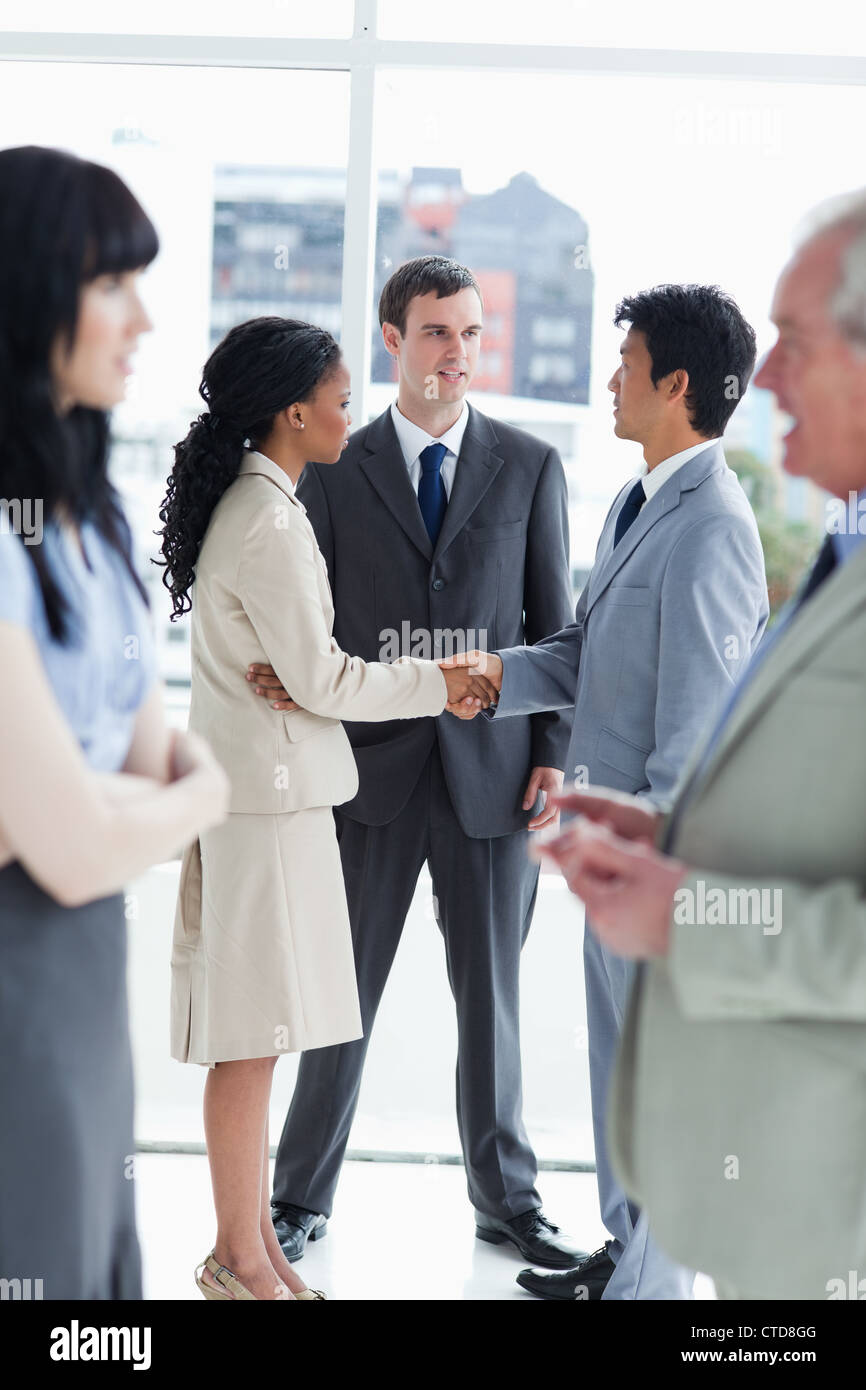 Two executives shaking hands and speaking to another man Stock Photo ...