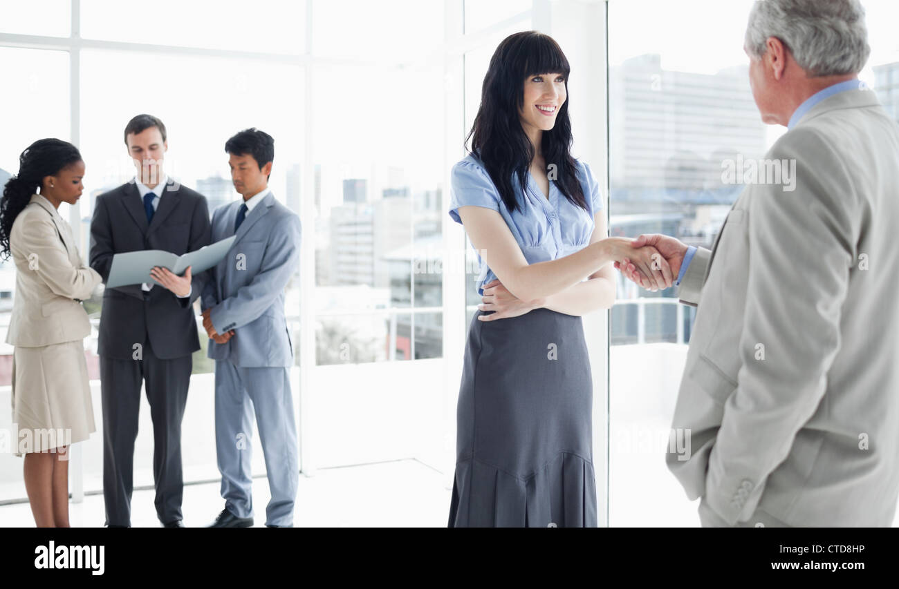 Two business people shaking hands and three others looking at some ...