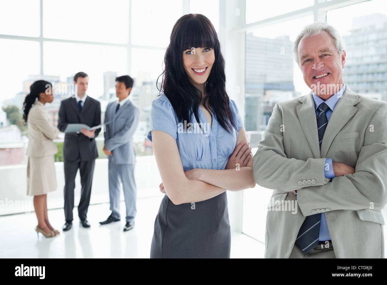 Two smiling business people standing upright and three executives ...