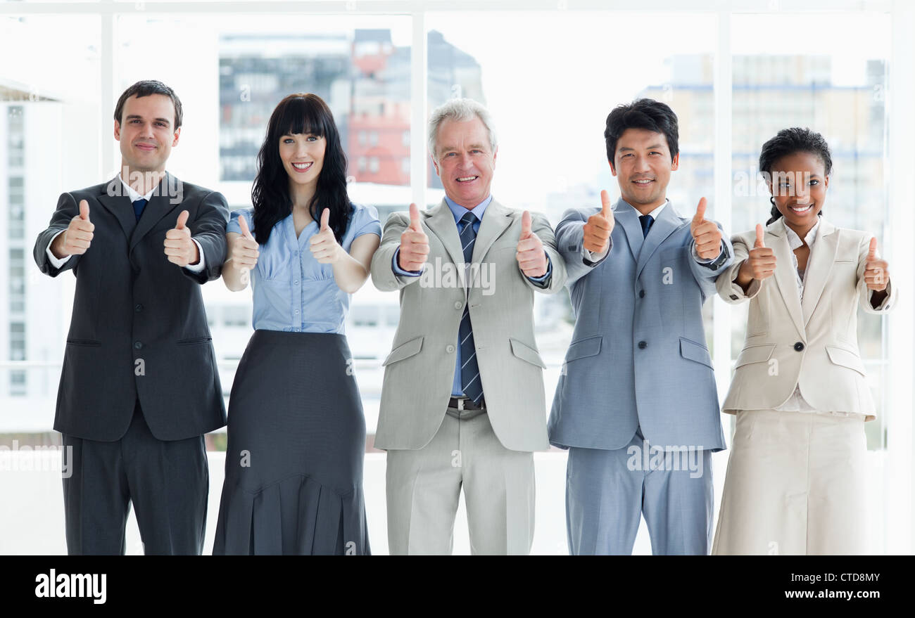 Smiling business people showing their approval with their thumbs up ...