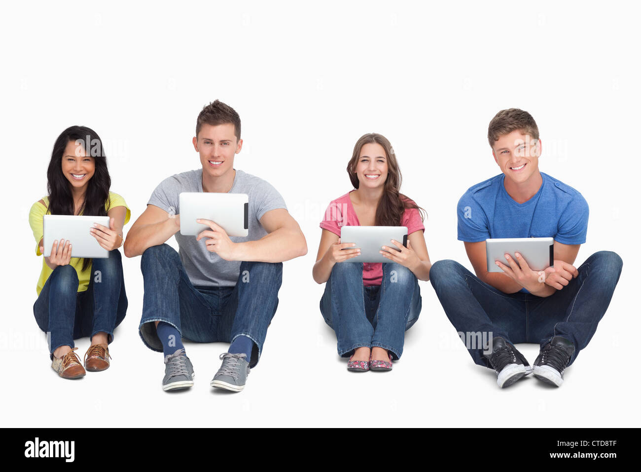 A group of people sitting beside each other with tablets while looking ...