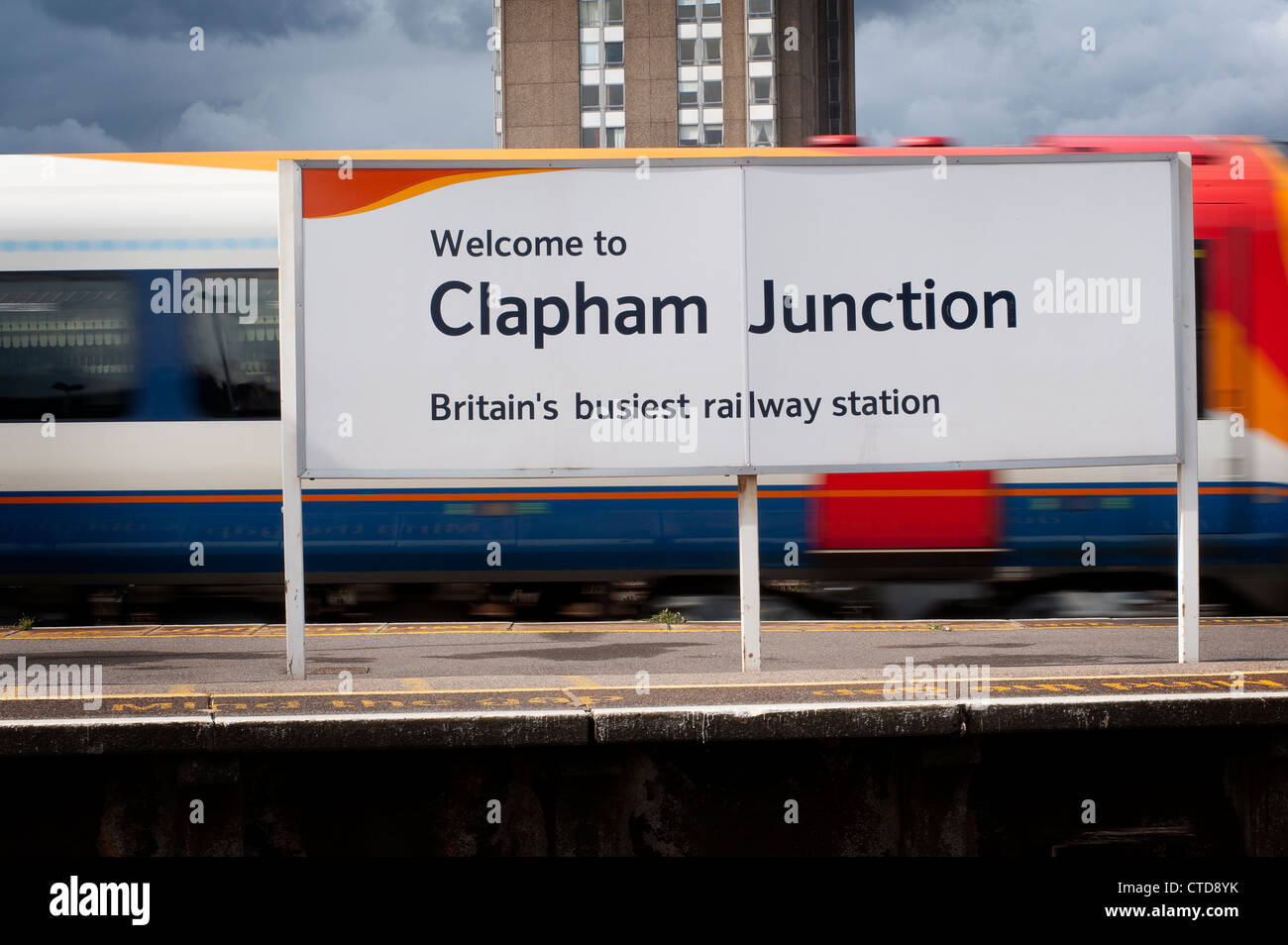 Welcome sign on the platform of Clapham Junction with train blurring ...