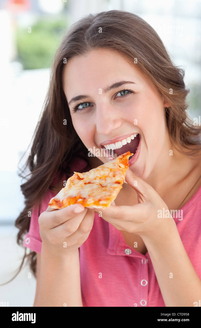 A woman about to eat a piece of pizza as she looks at the camera Stock ...