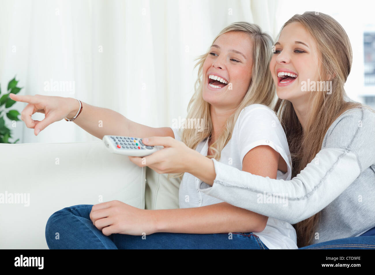 Sisters laughing at the tv together Stock Photo - Alamy