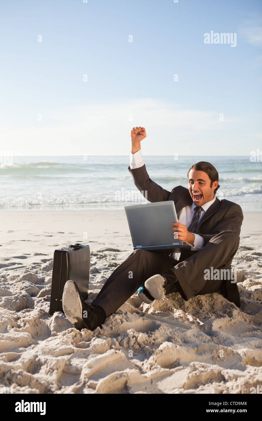 Successful businessman sitting on the beach while smiling Stock Photo ...