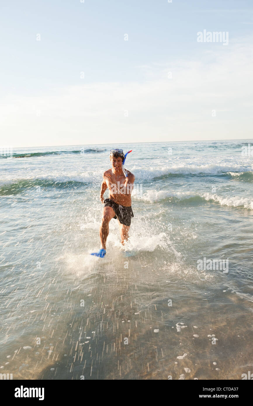 Young happy man running in the water with fins Stock Photo - Alamy