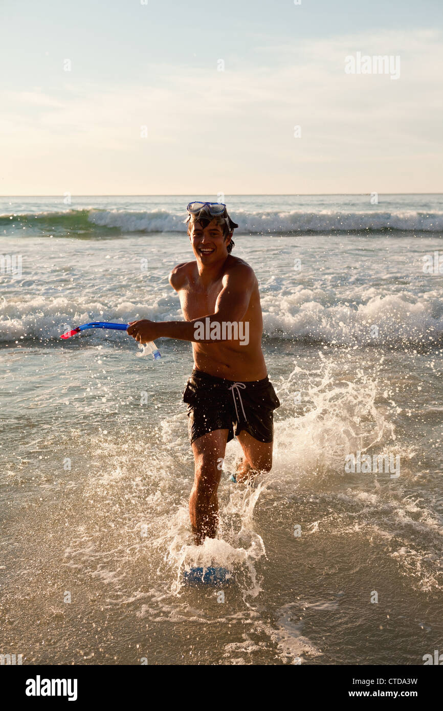 Young man running in the water while smiling Stock Photo - Alamy