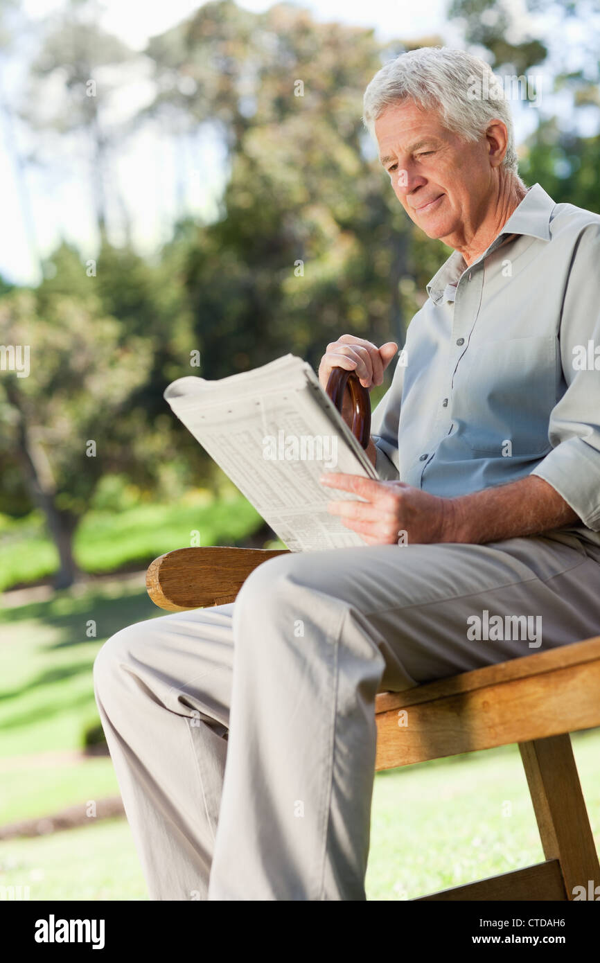 Old man sitting down smiling and holding a newspaper Stock Photo - Alamy