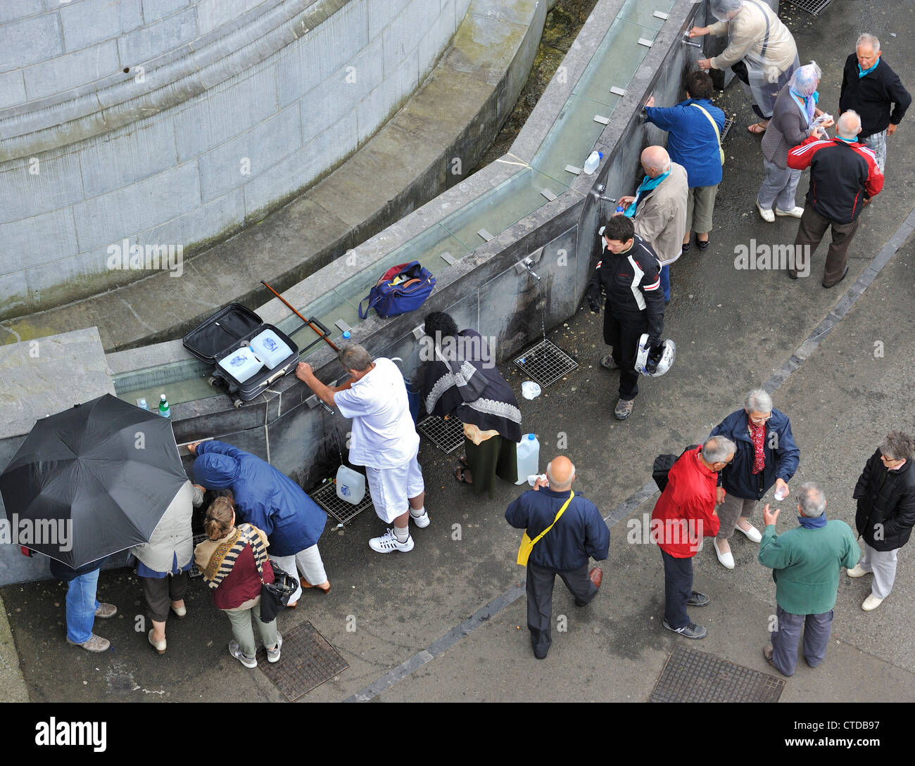 Pilgrims filling bottles with healing water at spring of the Sanctuary ...