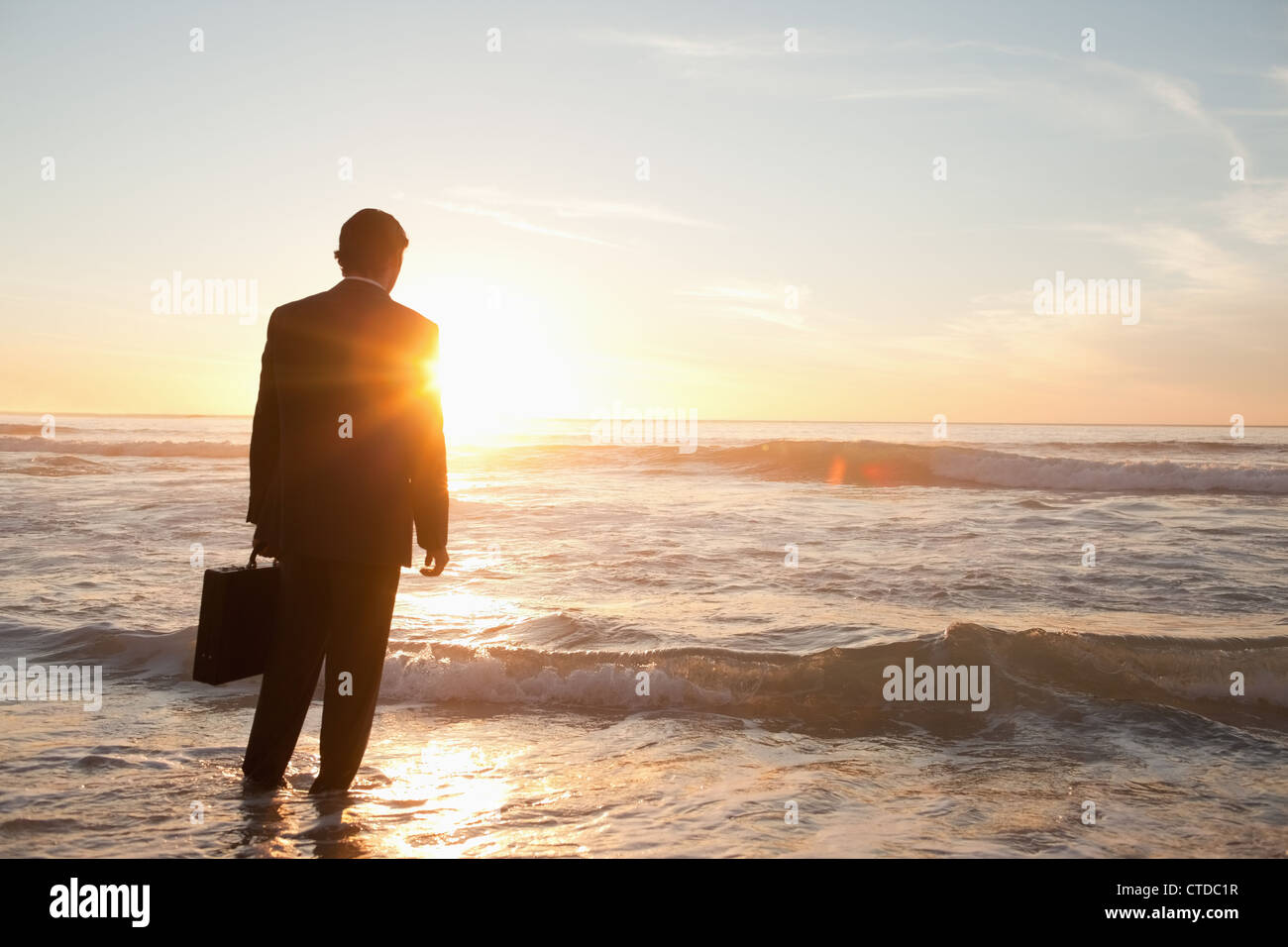 A man standing at the beach watching the sunrise hi-res stock ...