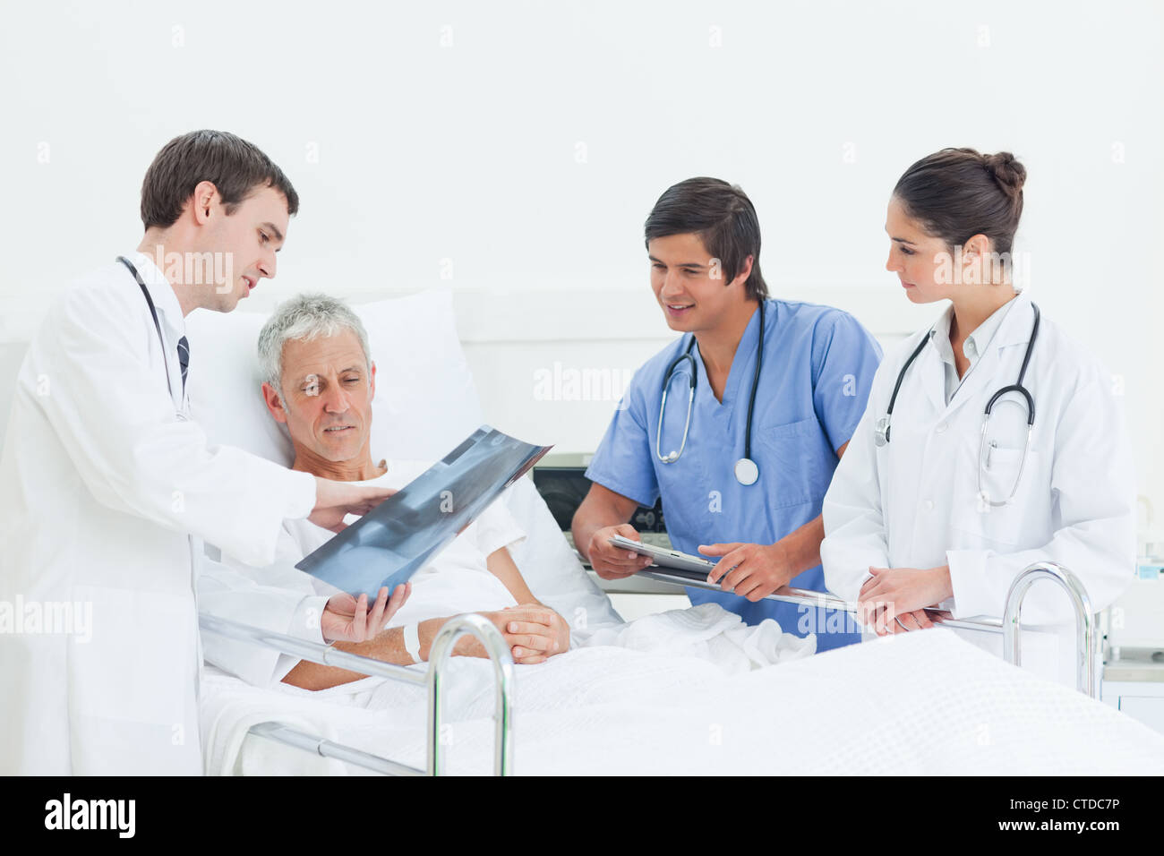 Doctor showing a x-ray scan to a patient while being watched by a ...
