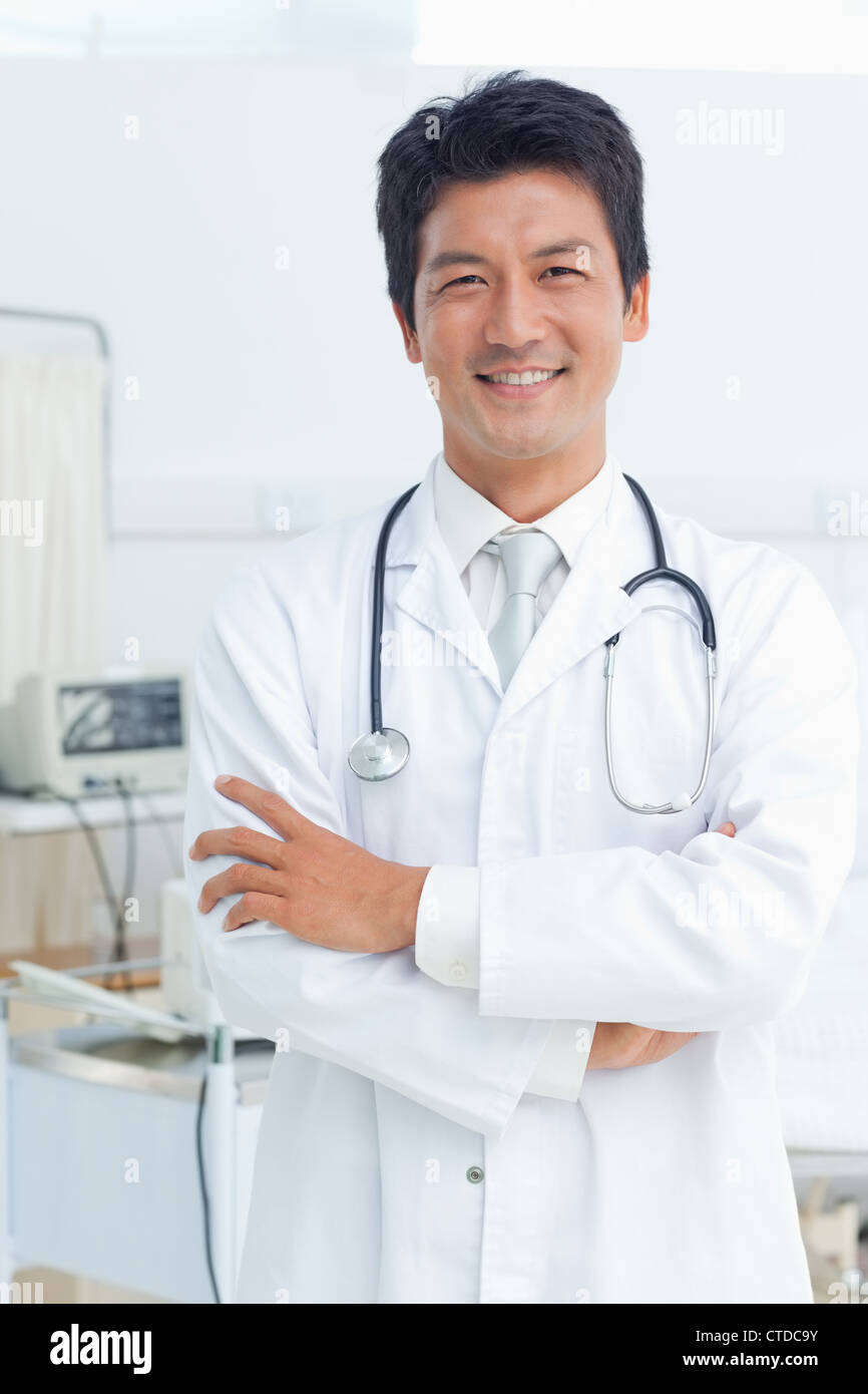 Smiling doctor crossing his arms as he looks ahead Stock Photo - Alamy
