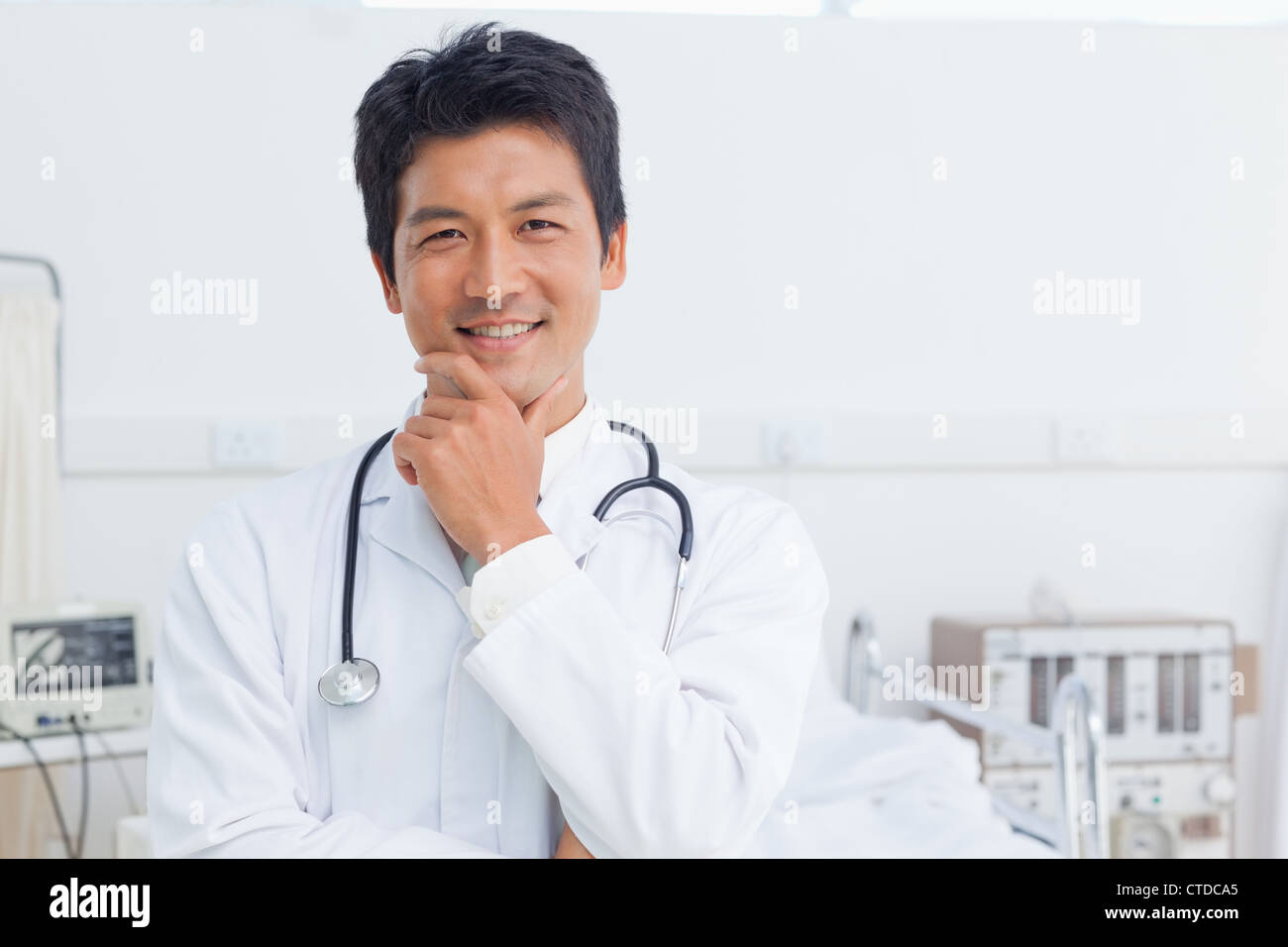 Doctor smiling as he holds his chin with his hand Stock Photo - Alamy
