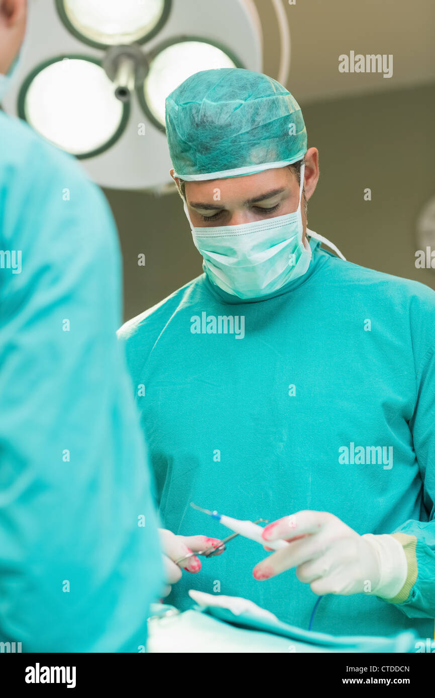 Serious surgeon looking at surgical tools Stock Photo - Alamy