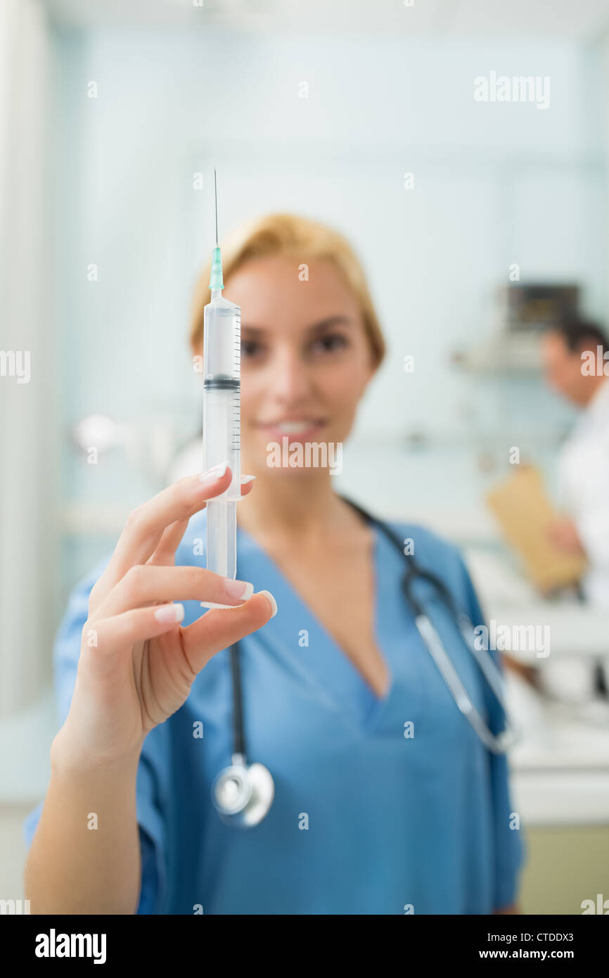Blonde nurse smiling while holding a syringe Stock Photo - Alamy