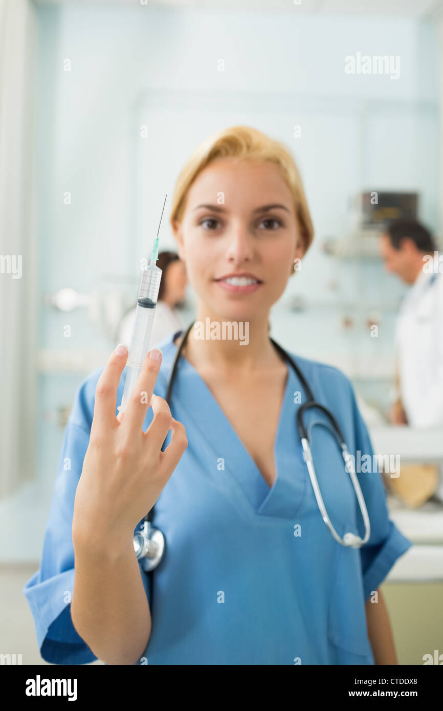 Blonde nurse looking at camera while holding a syringe Stock Photo - Alamy