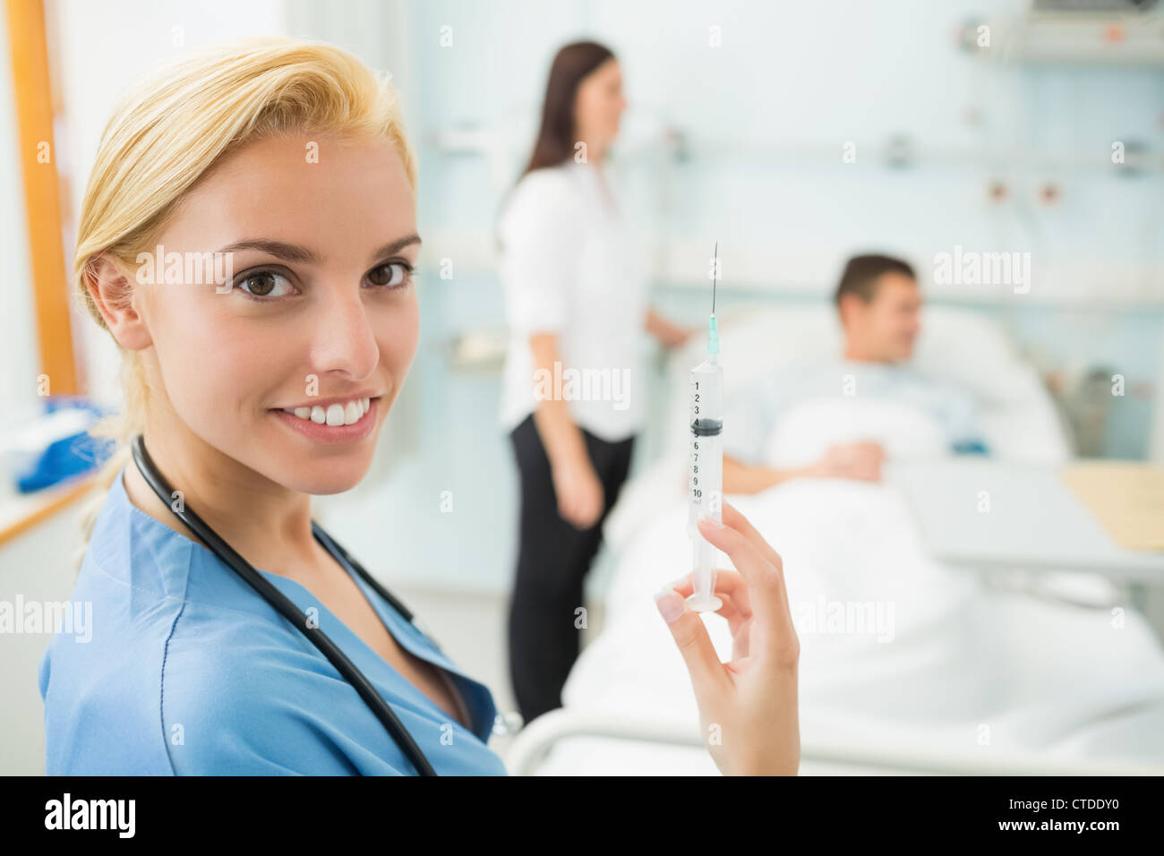 Nurse holding a syringe while smiling Stock Photo - Alamy