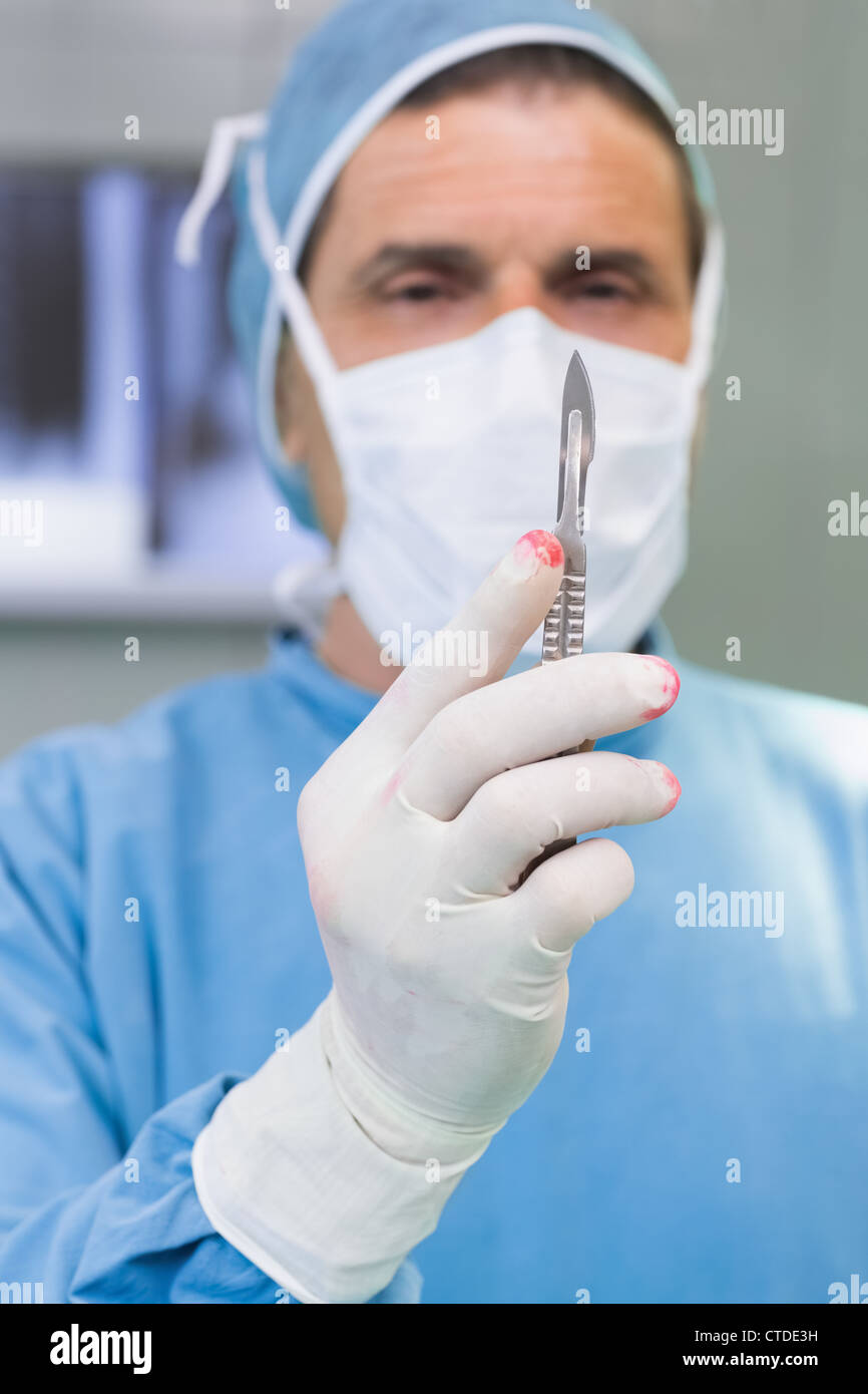 Surgeon holding a scalpel in his gloved hand Stock Photo - Alamy