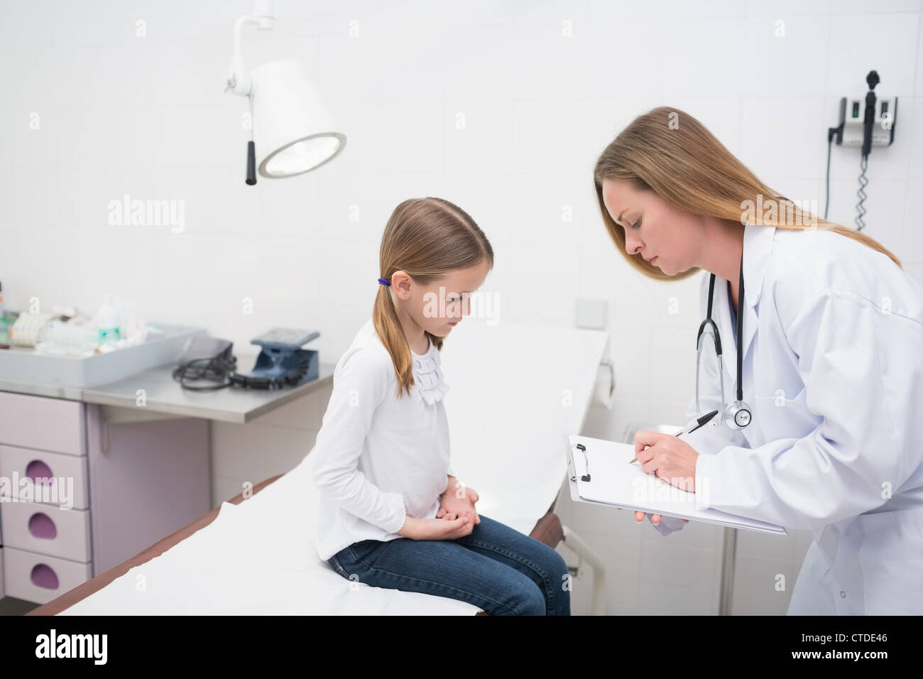 Doctor writing in a notepad in front of a girl sitting Stock Photo - Alamy