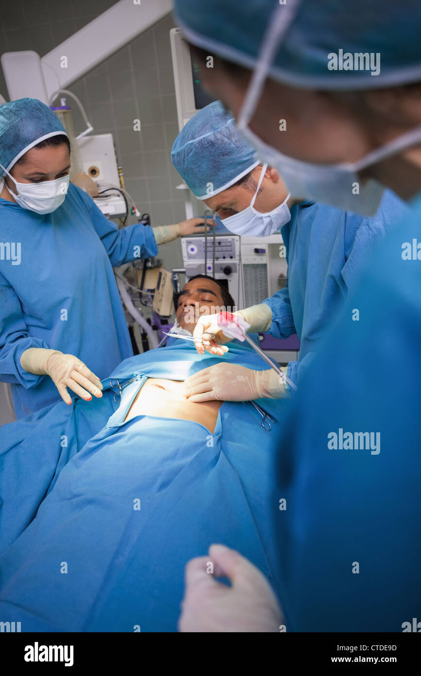 Team of surgeons working on an unconscious male patient Stock Photo - Alamy