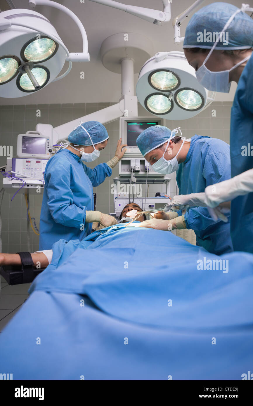 Group of surgeons working on an unconscious male patient Stock Photo ...