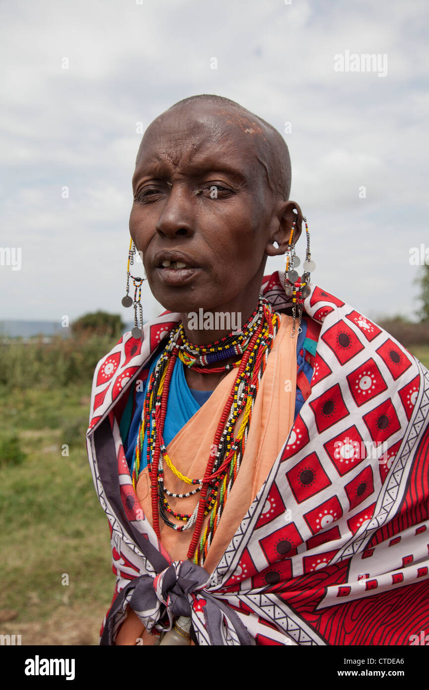 Masai wife of elder chief in traditional costume outside his hut in a ...