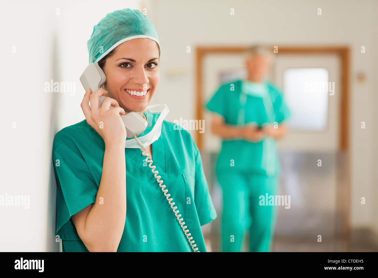 Smiling surgeon standing in a hallway while holding a phone Stock Photo ...