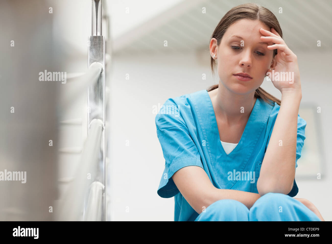 Nurse leaning her head on her hands in a stairwell Stock Photo - Alamy