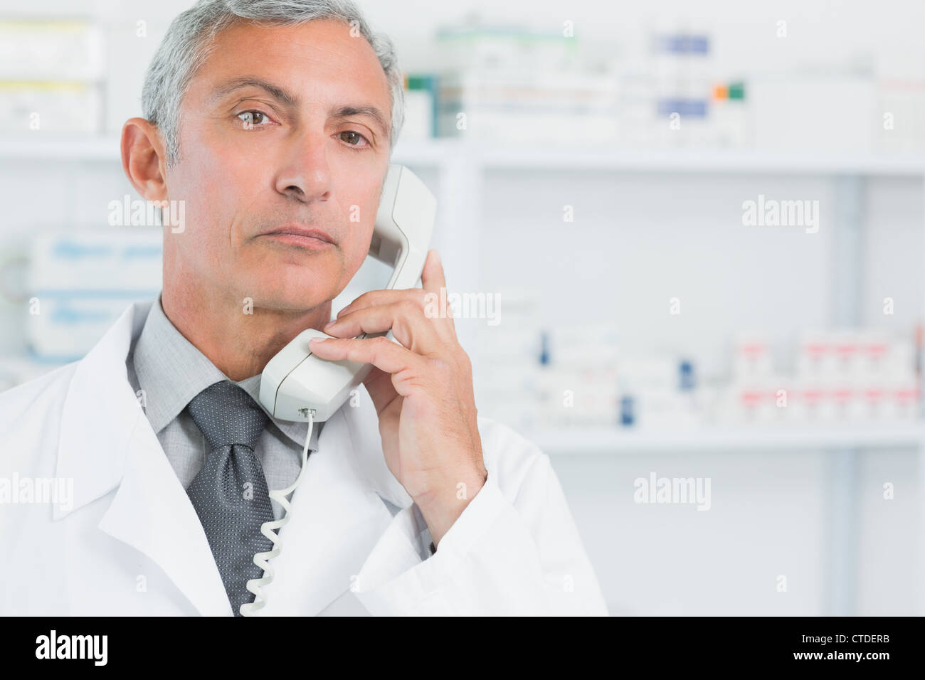 Pharmacist standing in a pharmacy while phoning Stock Photo - Alamy