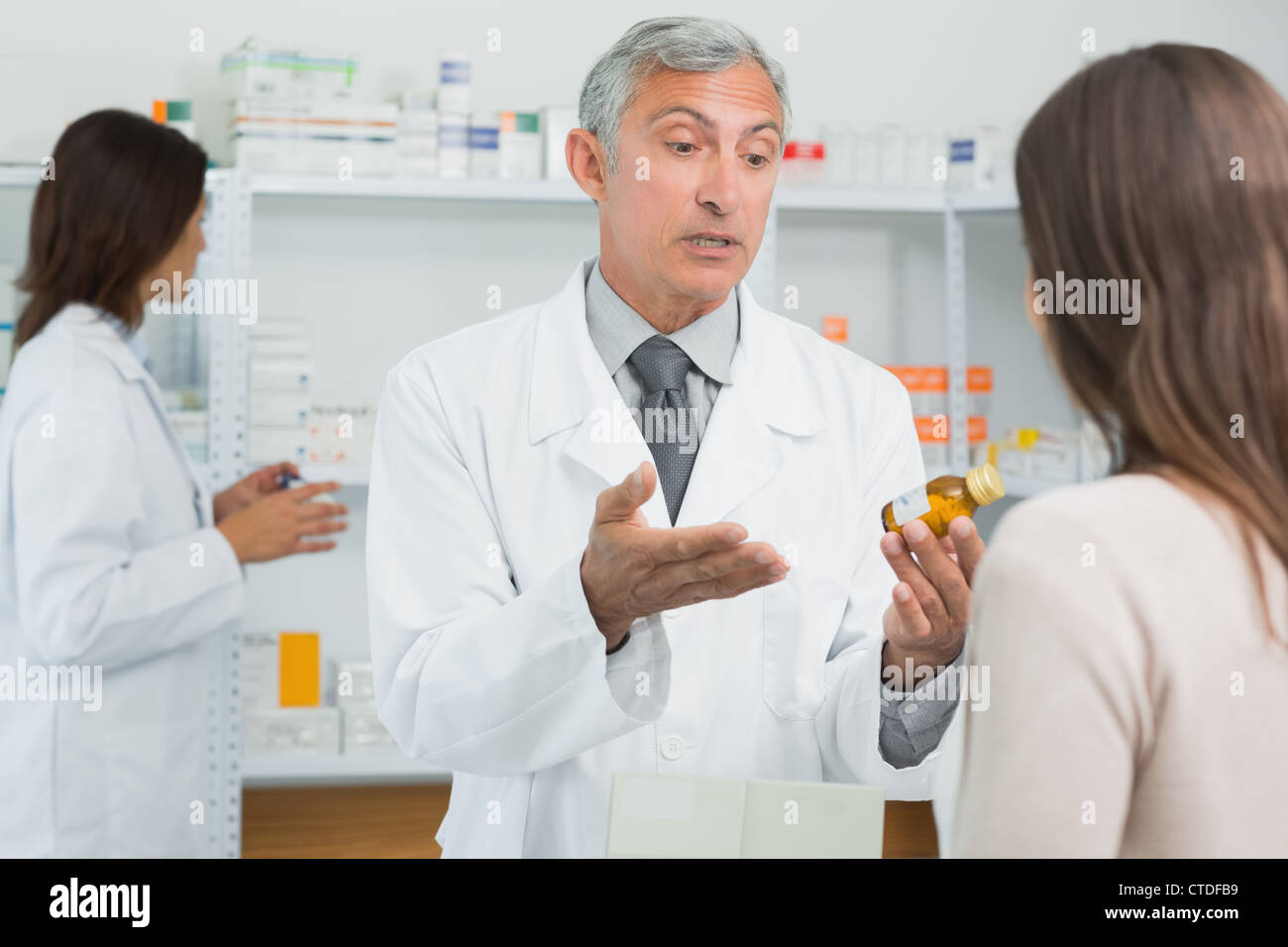 Hospital pharmacist talking to a customer while holding a flask of ...