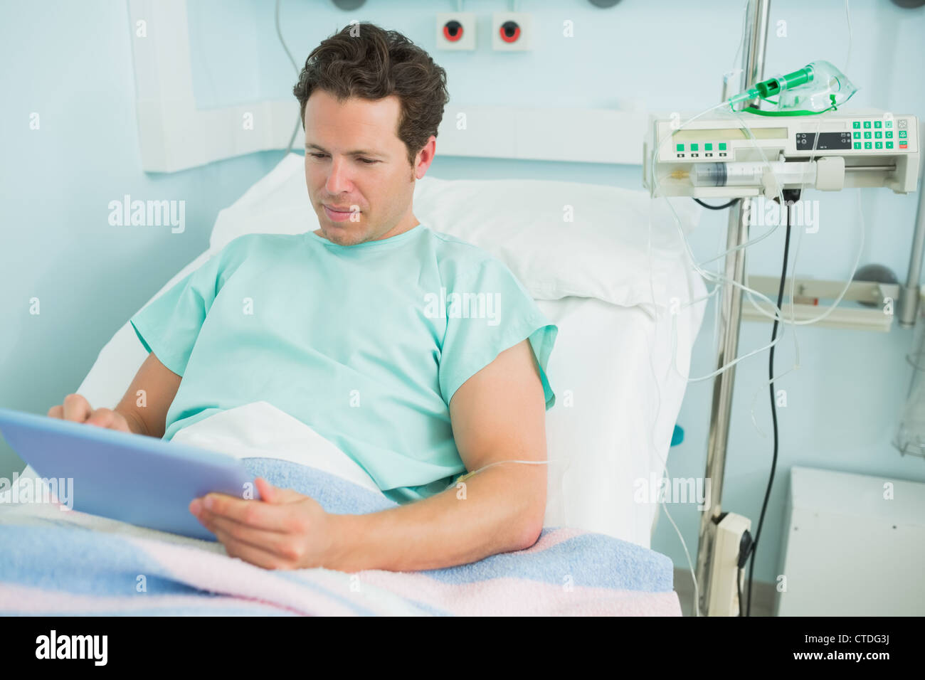 Patient using a tactile tablet while lying on a bed Stock Photo - Alamy