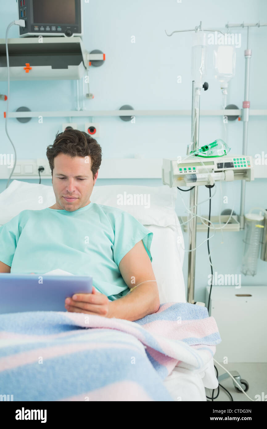Male patient using a tactile tablet while lying on a bed Stock Photo ...
