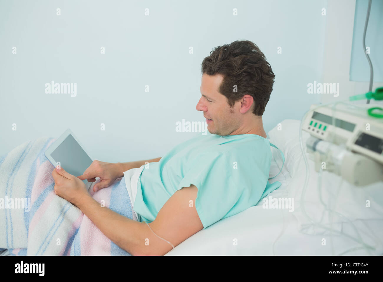 Male patient touching a tactile tablet while lying on a bed Stock Photo ...