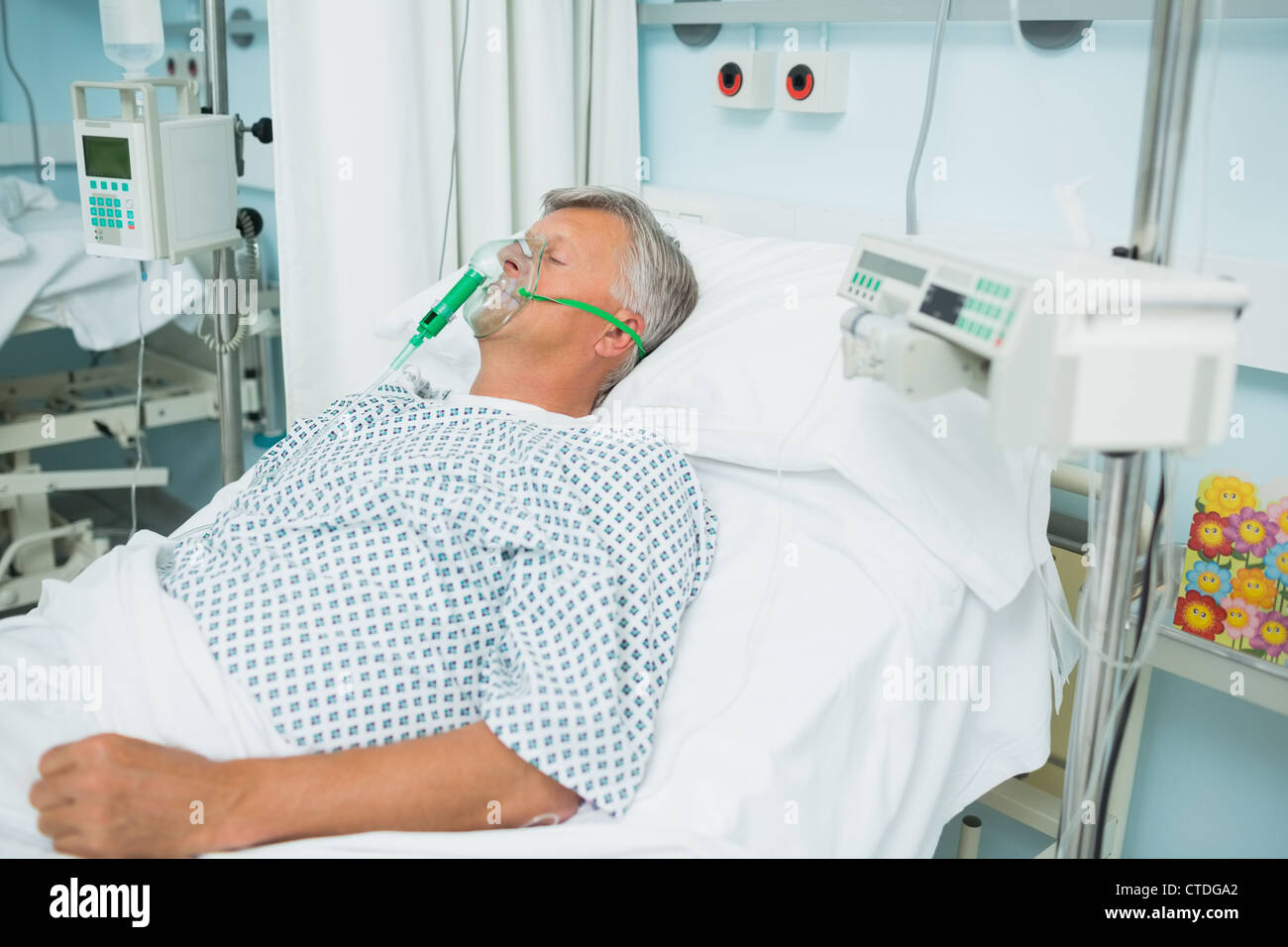 Unconscious patient lying on a bed with an oxygen mask on Stock Photo - Alamy
