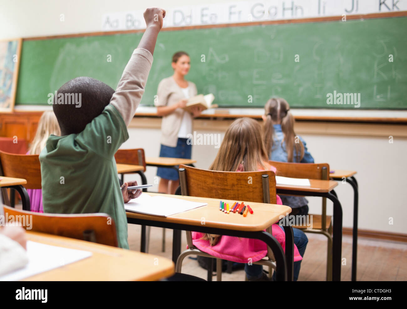 Back view of pupil raising hand Stock Photo - Alamy